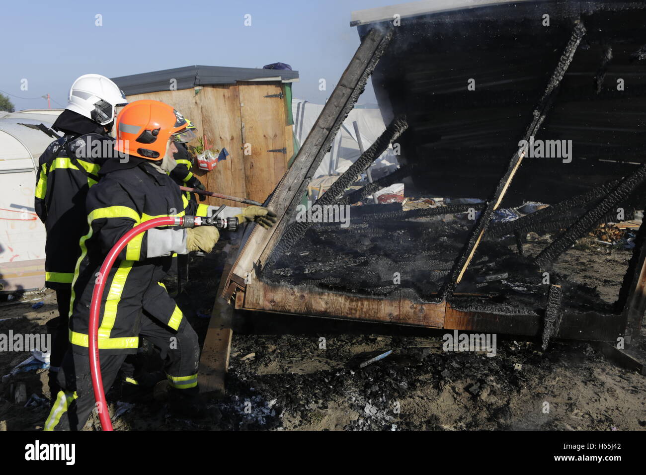 Calais, France. 25th October 2016. Fire officers pull down the remains ...