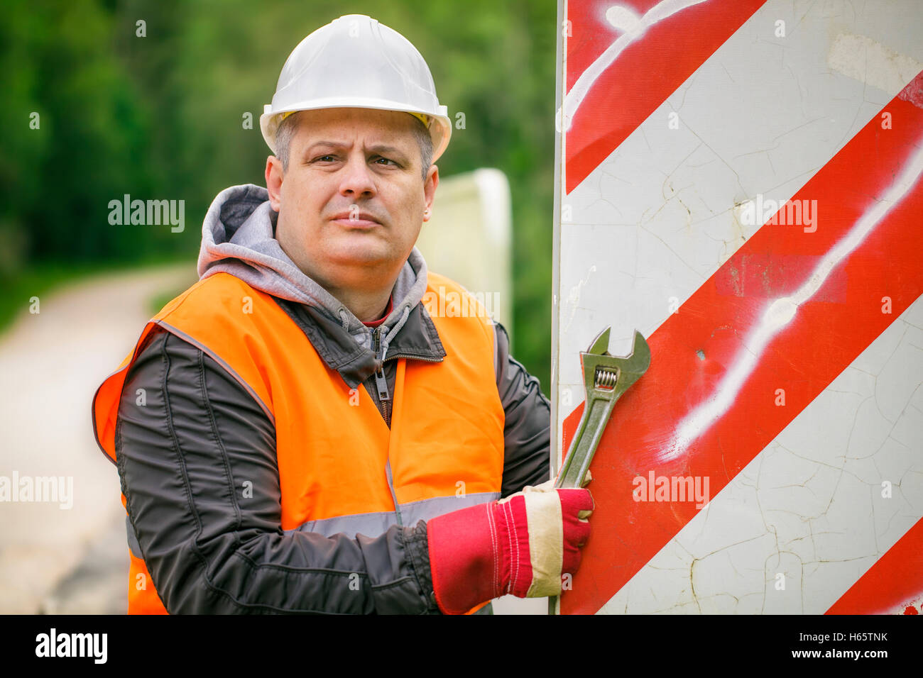 Worker with adjustable wrench on the bridge repairing road sign Stock ...
