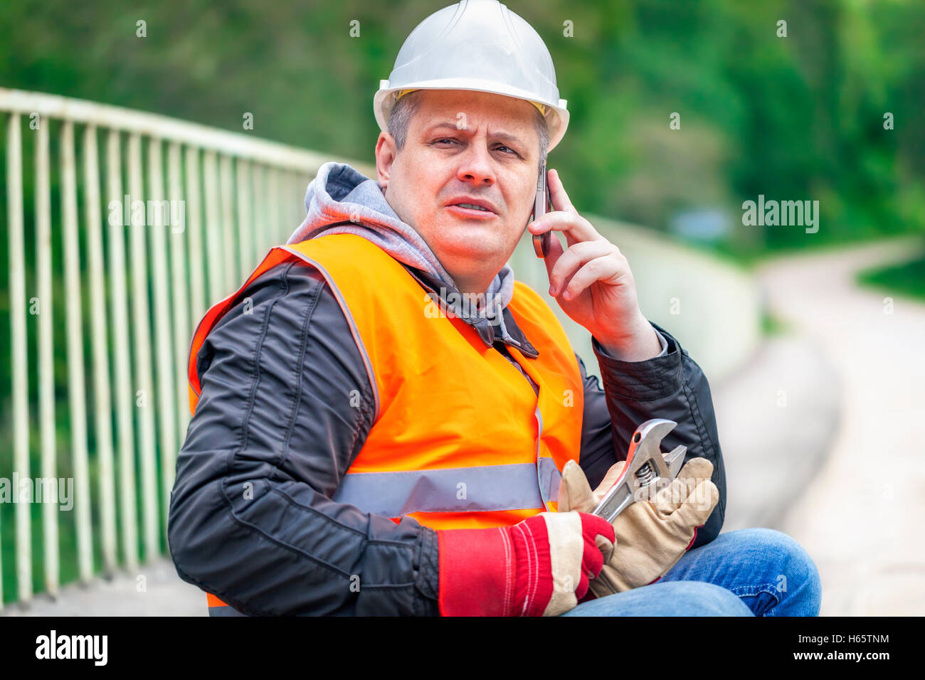Worker with wrench and a telephone on the bridge Stock Photo - Alamy