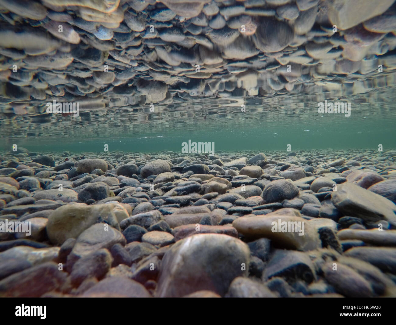 cold underwater river bed with perfect reflection on surface tension ...