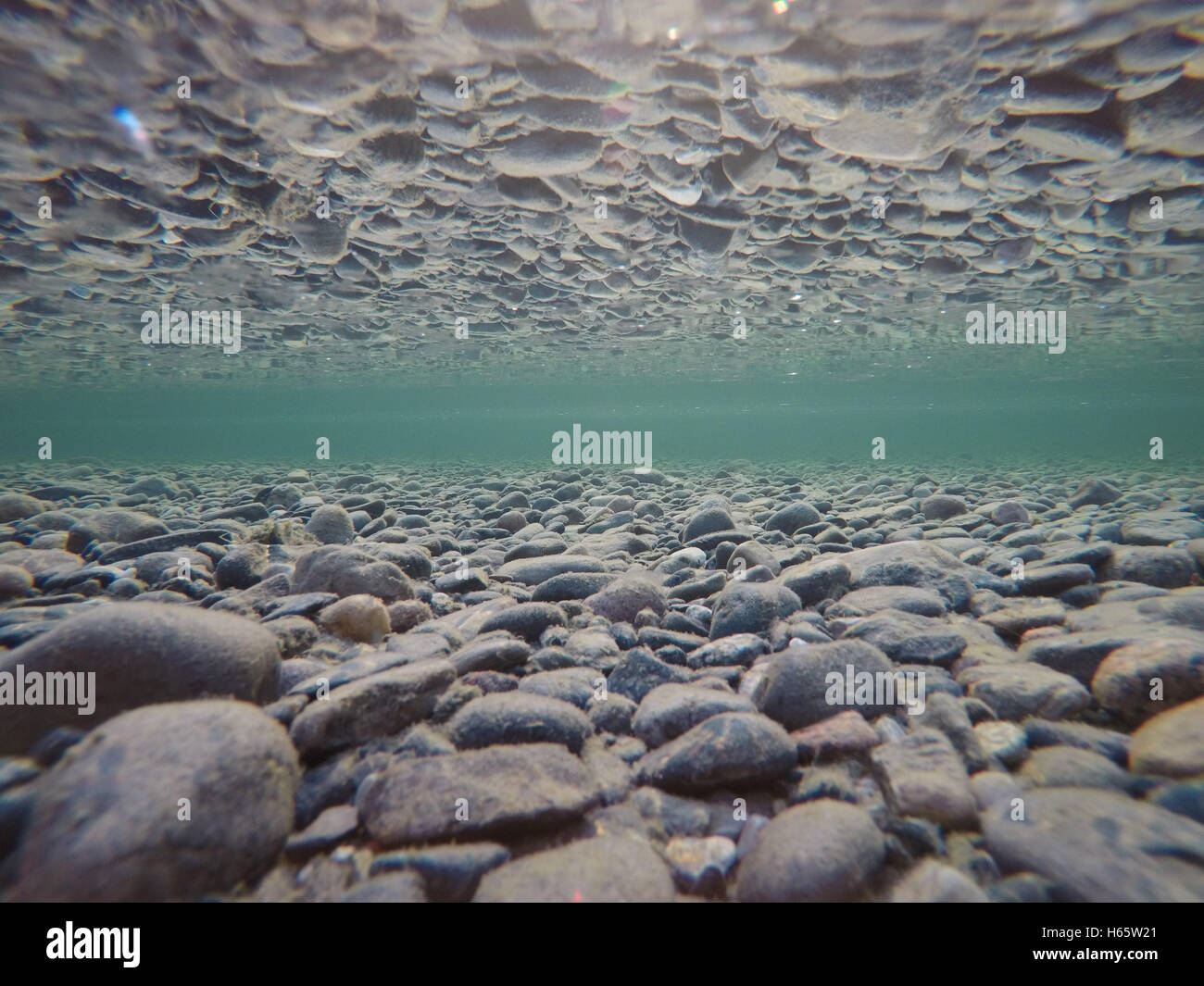 cold underwater river bed with perfect reflection on surface tension ...