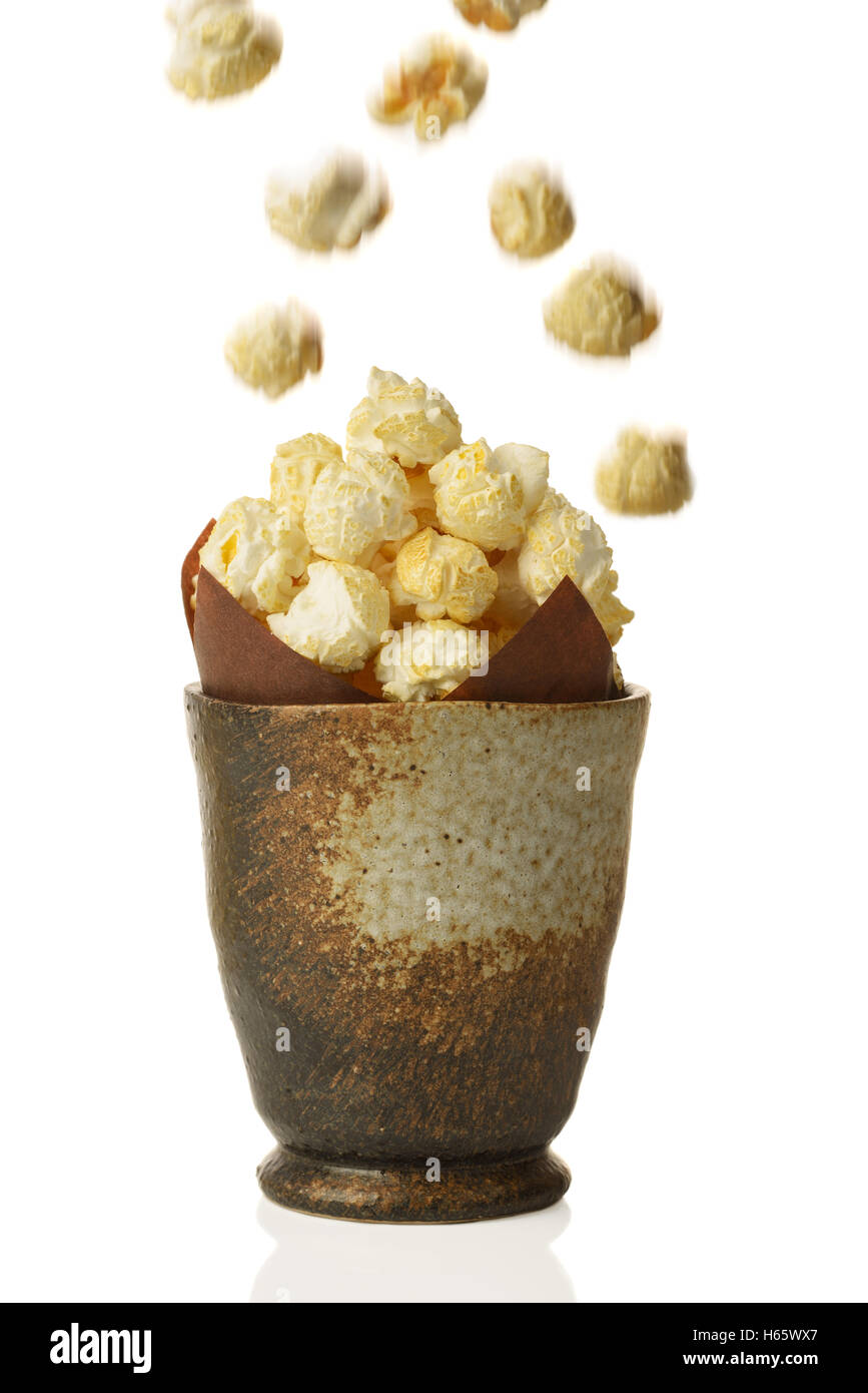 Popcorn falling into filled pot on a white background Stock Photo - Alamy