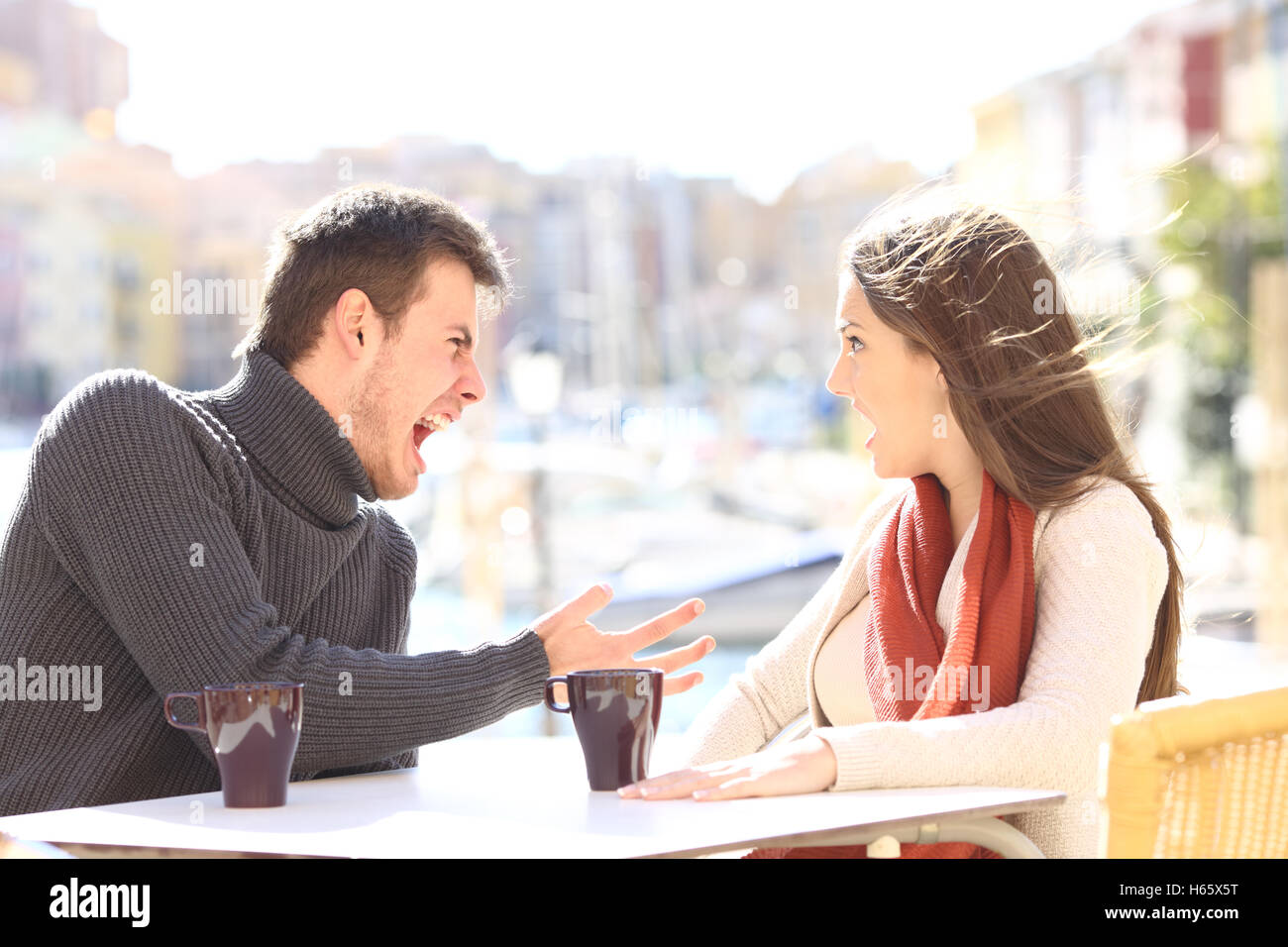 Angry casual couple arguing and shouting each other in a bar terrace ...