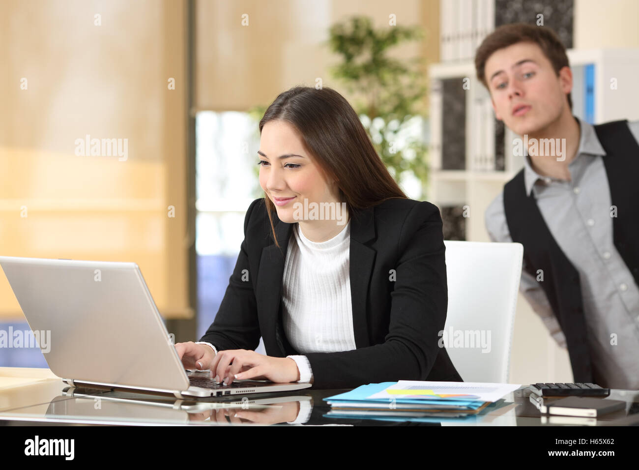 Businessman spying his colleague who is working at her desktop at job ...