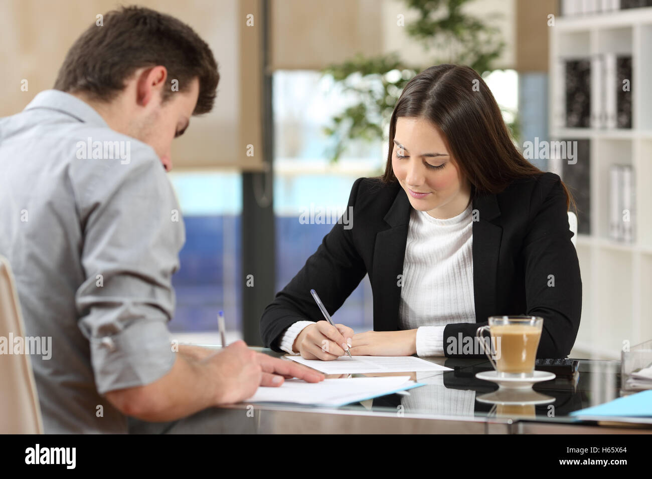 Businesspeople signing contracts together after a deal in a desktop at ...