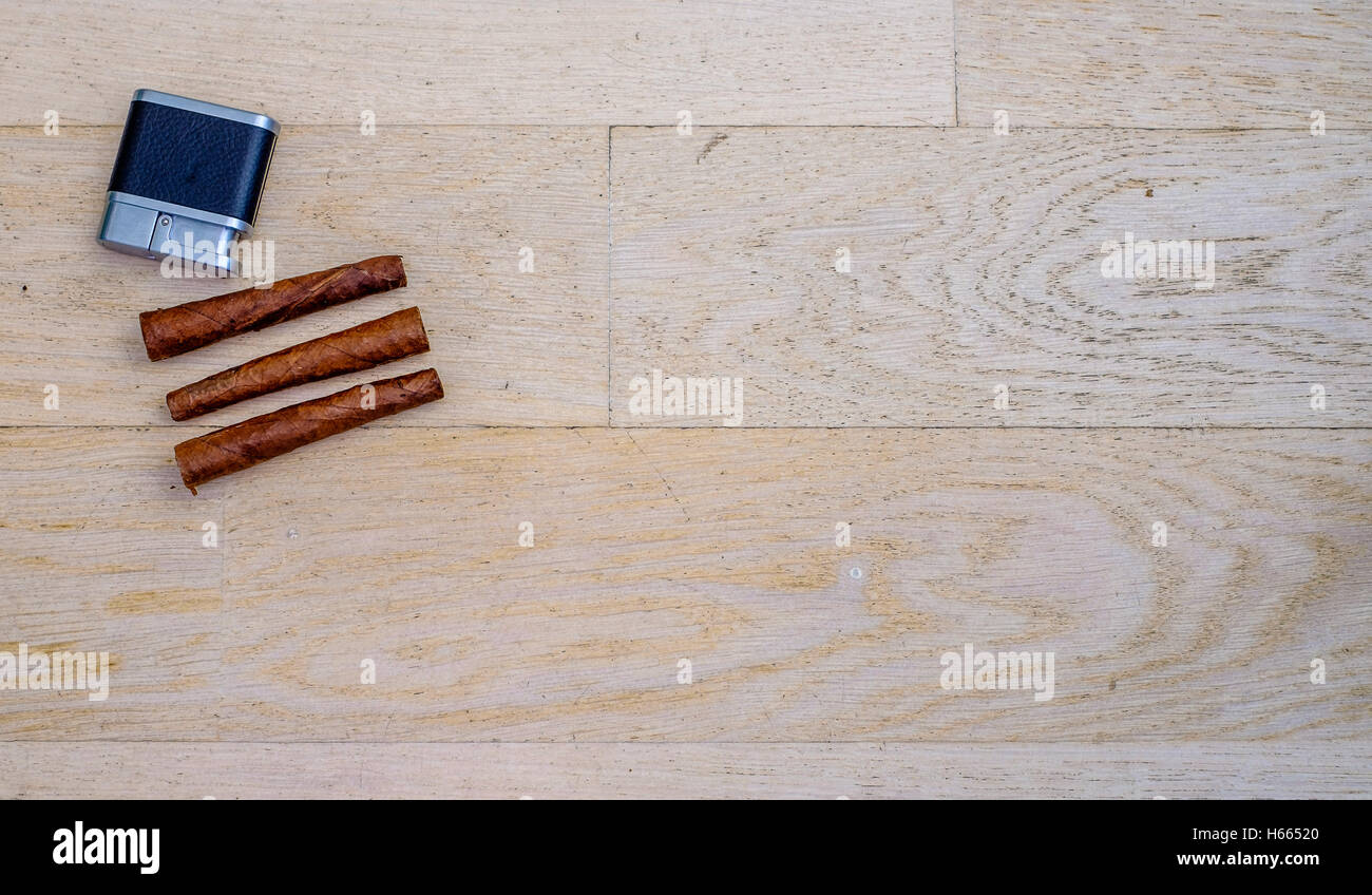 three Tuscan cigars and a lighter on a wooden floor Stock Photo - Alamy
