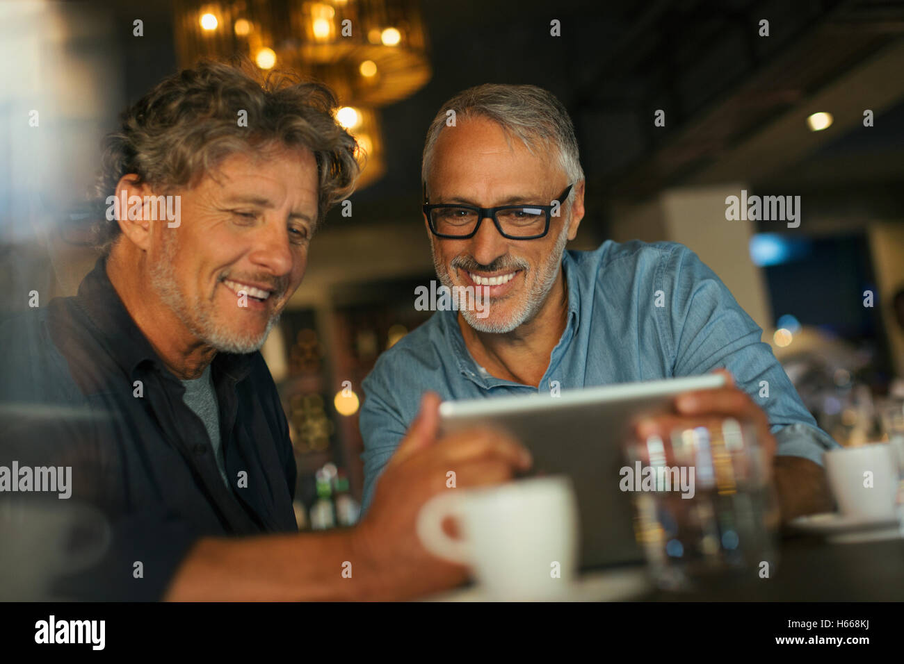 Men using digital tablet at restaurant table Stock Photo - Alamy