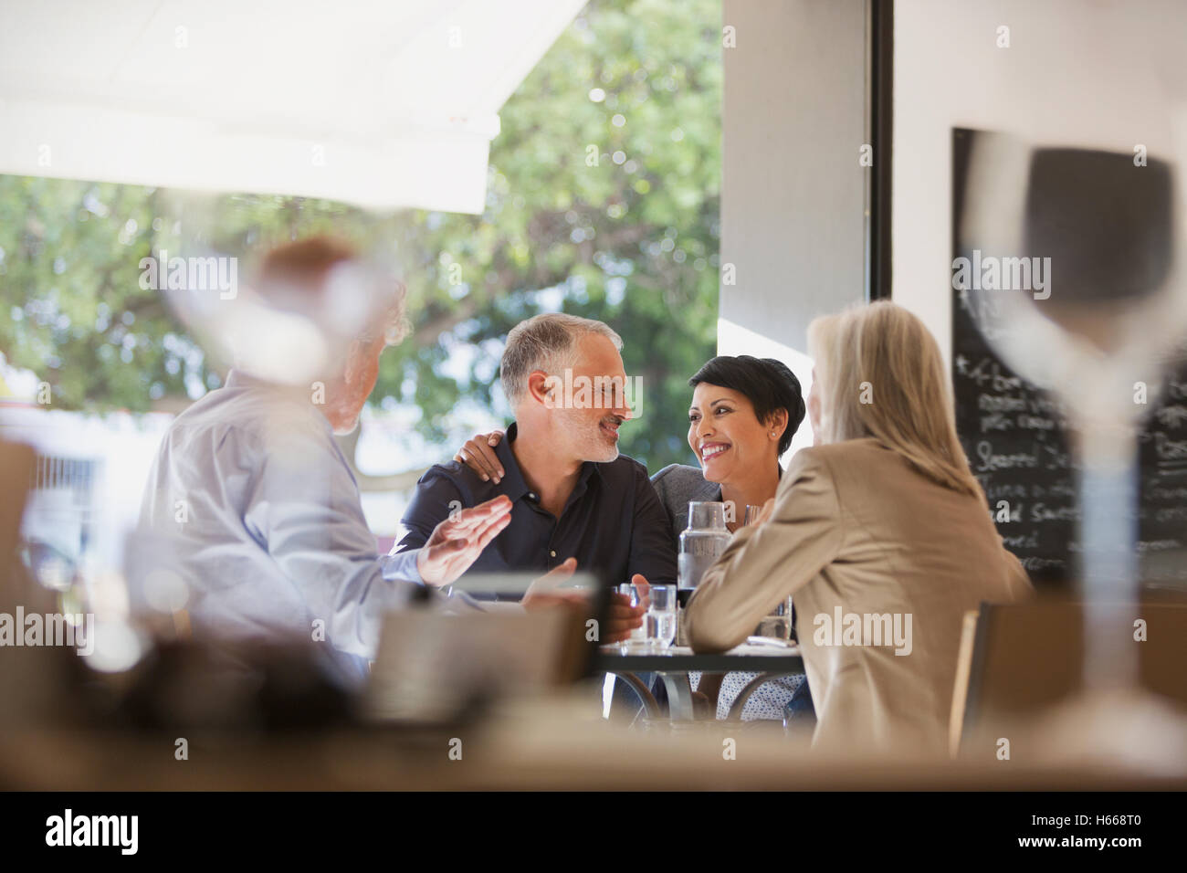Affectionate couple dining with friends at restaurant table Stock Photo ...
