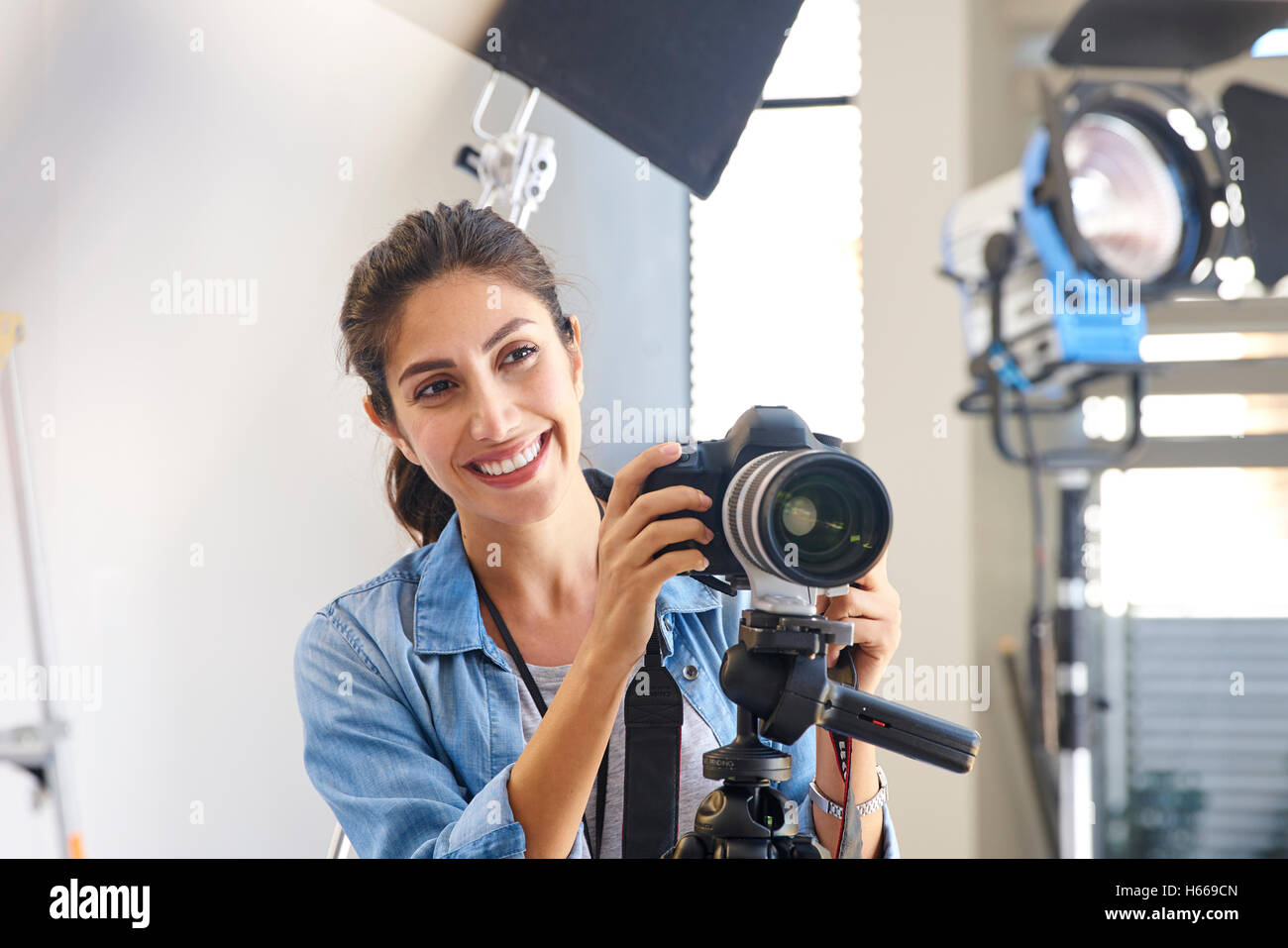 Smiling female photographer behind camera in studio Stock Photo - Alamy