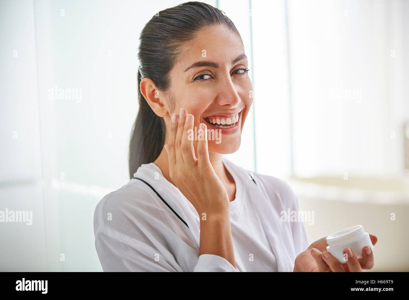 Portrait smiling woman apply face cream to cheek Stock Photo - Alamy
