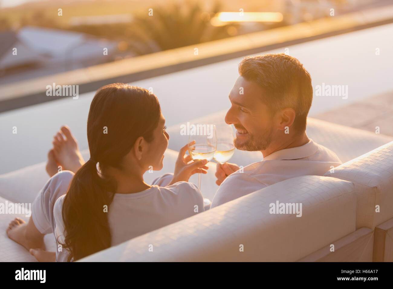 Couple relaxing toasting white wine glasses on chaise lounge on luxury ...