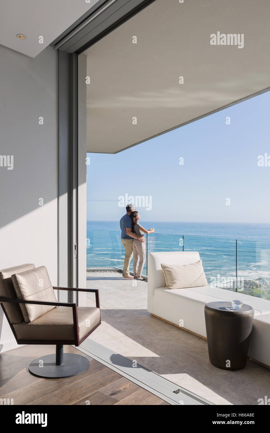 Couple enjoying sunny ocean view from luxury home showcase balcony ...