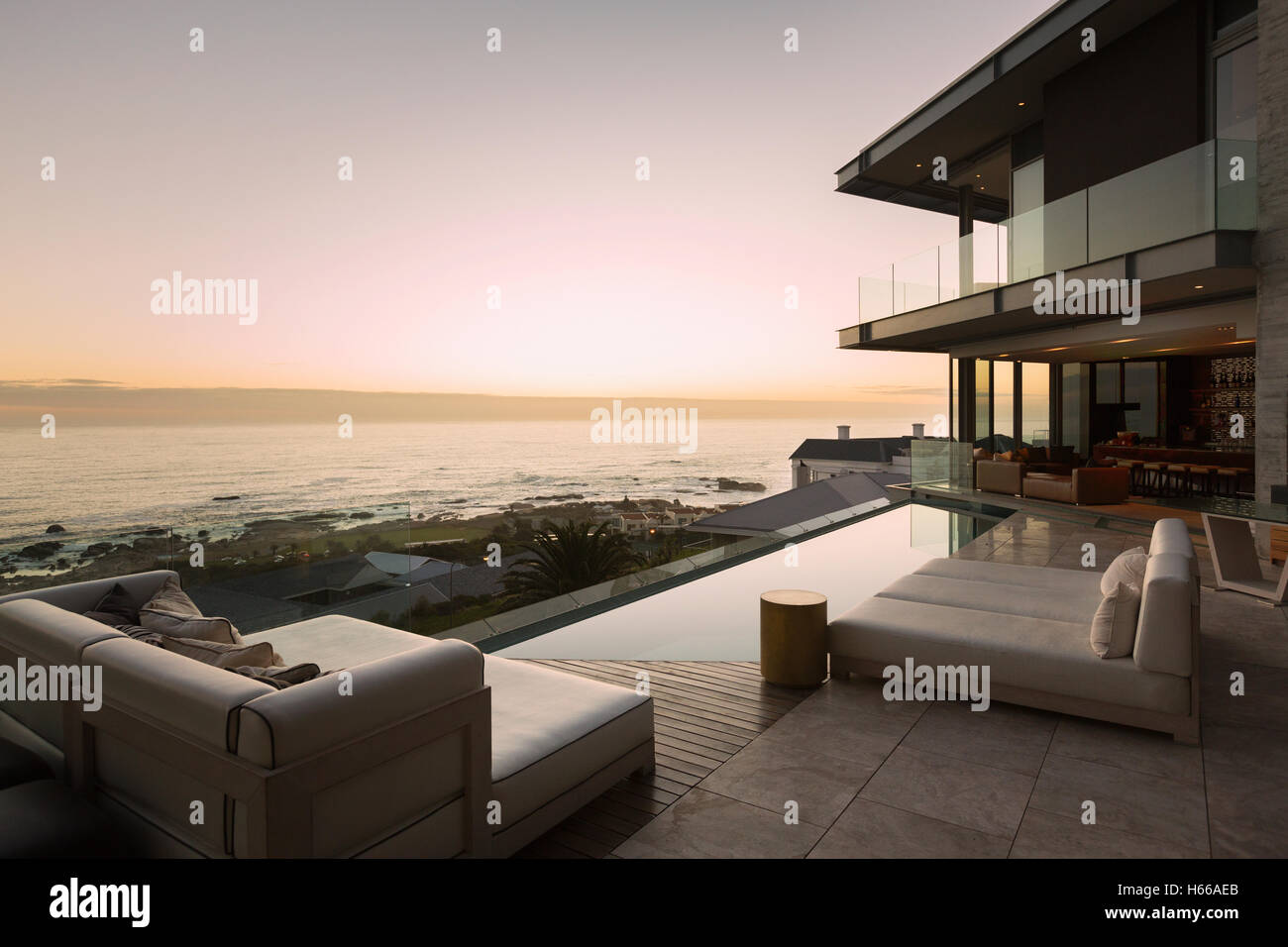 Tranquil sunset ocean view beyond modern luxury home showcase patio ...