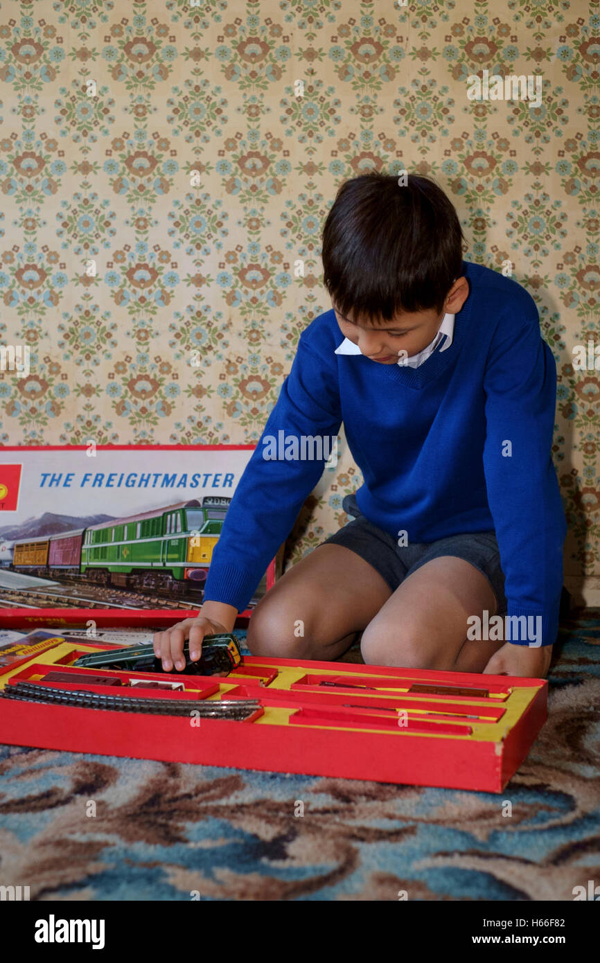 young boy playing with electric train set in a 1970s setting england uk ...