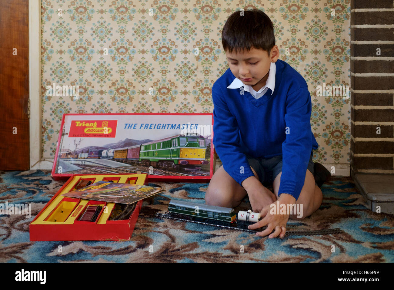 young boy playing with electric train set in a 1970s setting england uk ...