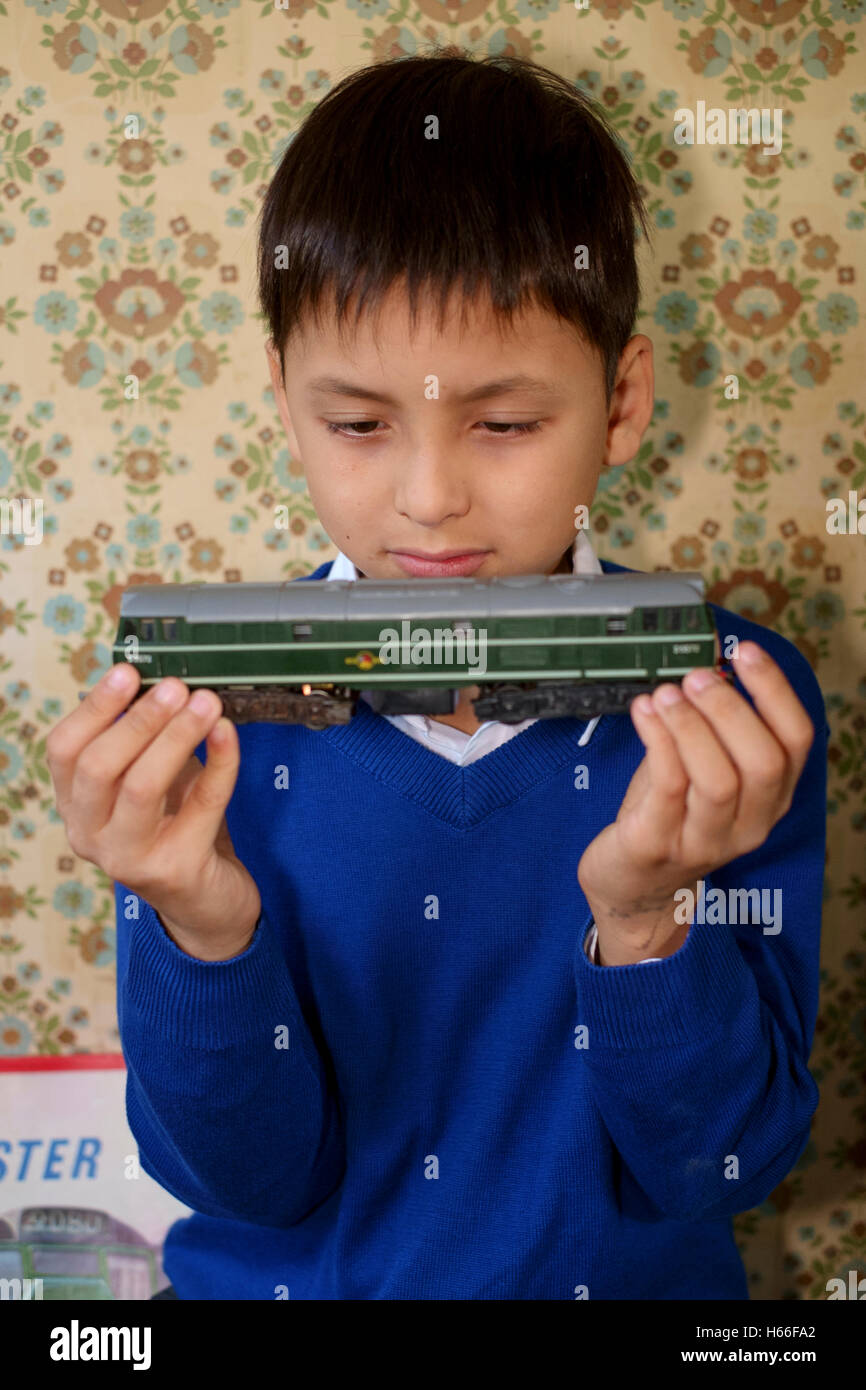 young boy playing with electric train set in a 1970s setting england uk ...