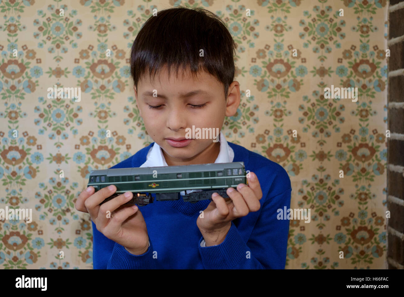 young boy playing with electric train set in a 1970s setting england uk ...