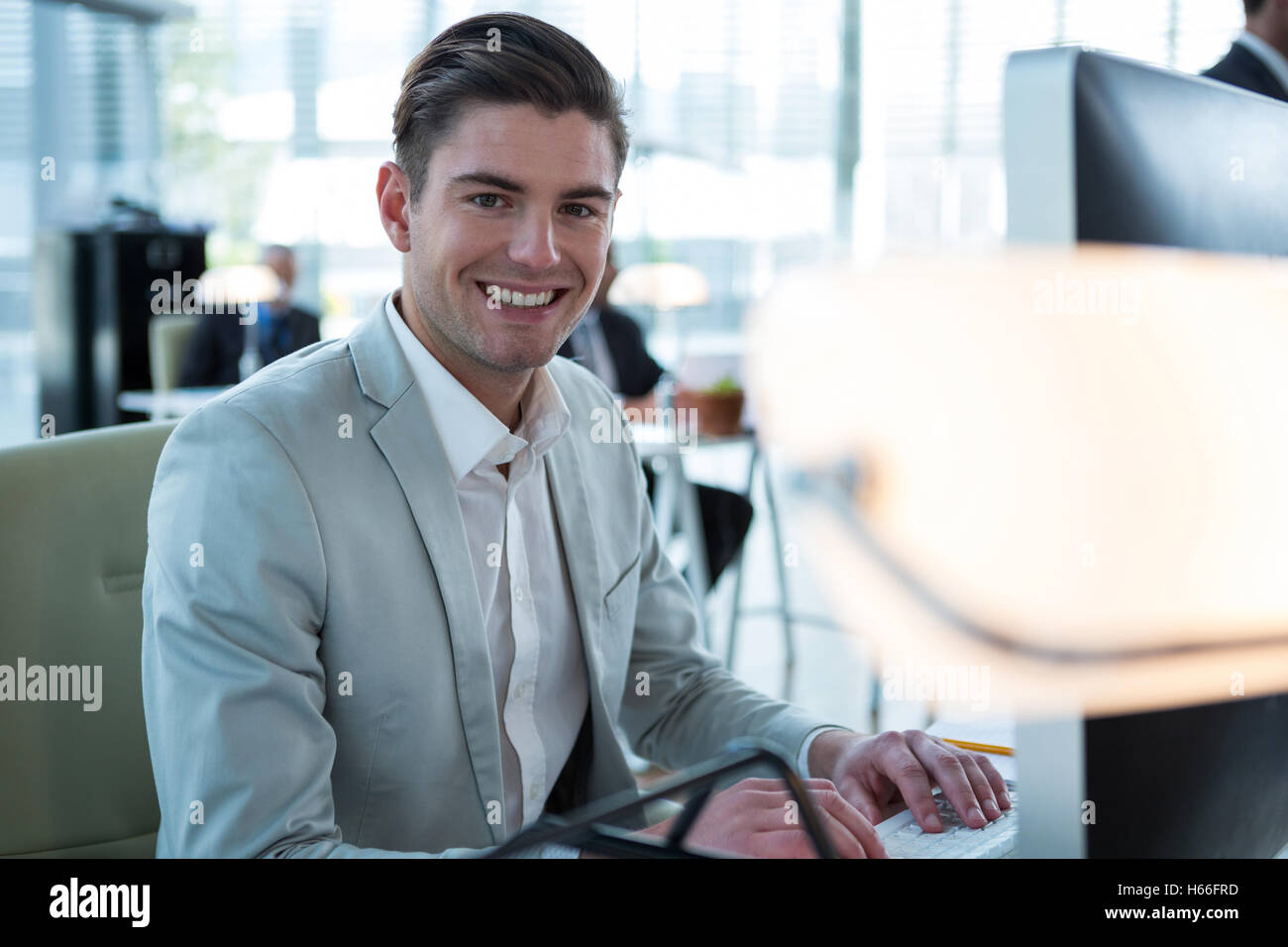 Smiling businessman working on computer in the office Stock Photo - Alamy