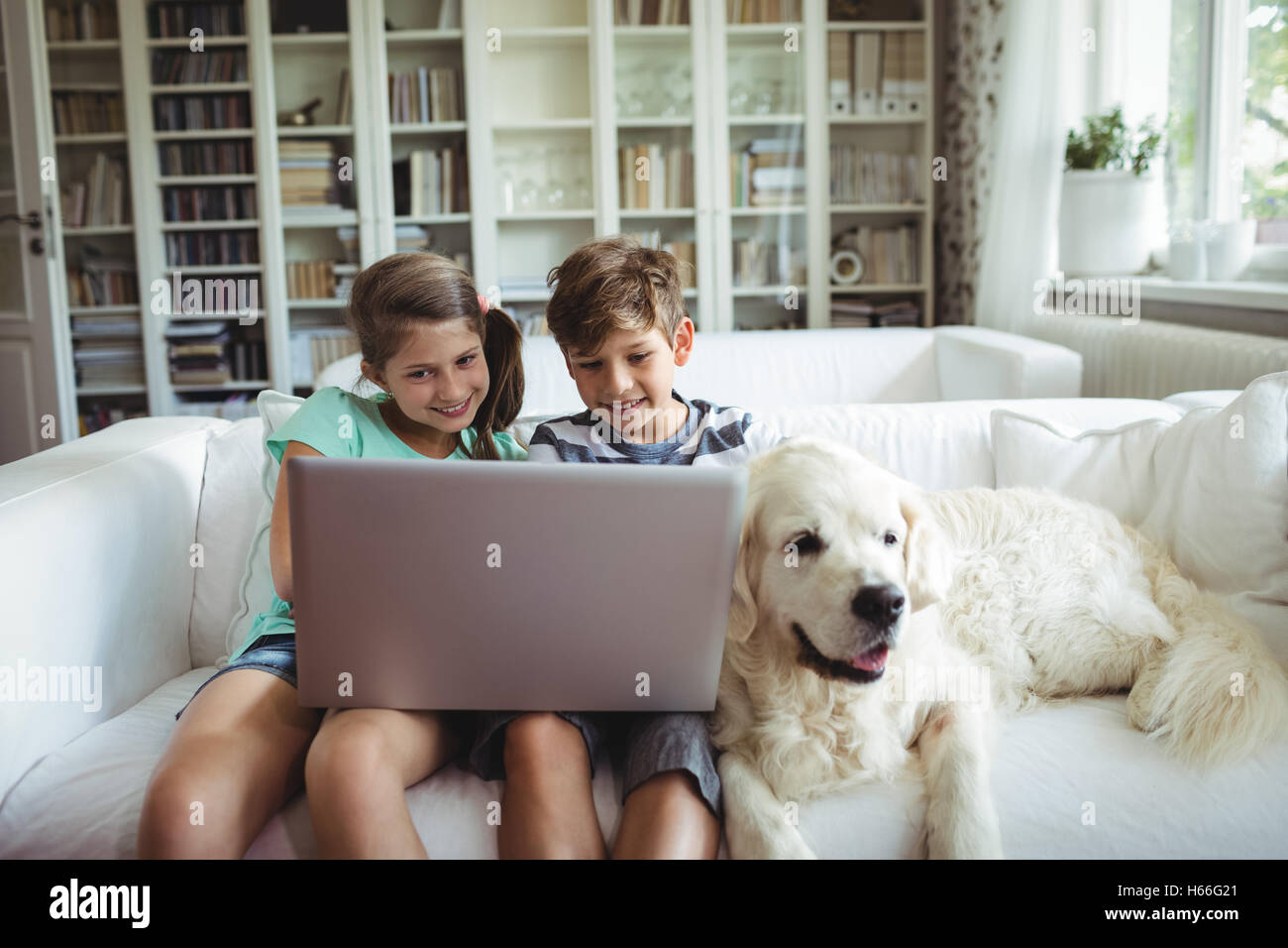 Children using laptop while sitting on a sofa Stock Photo - Alamy