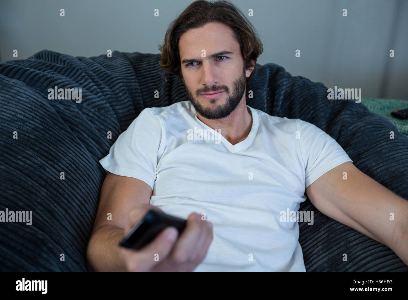 Man changing a channel while watching tv in living room Stock Photo - Alamy