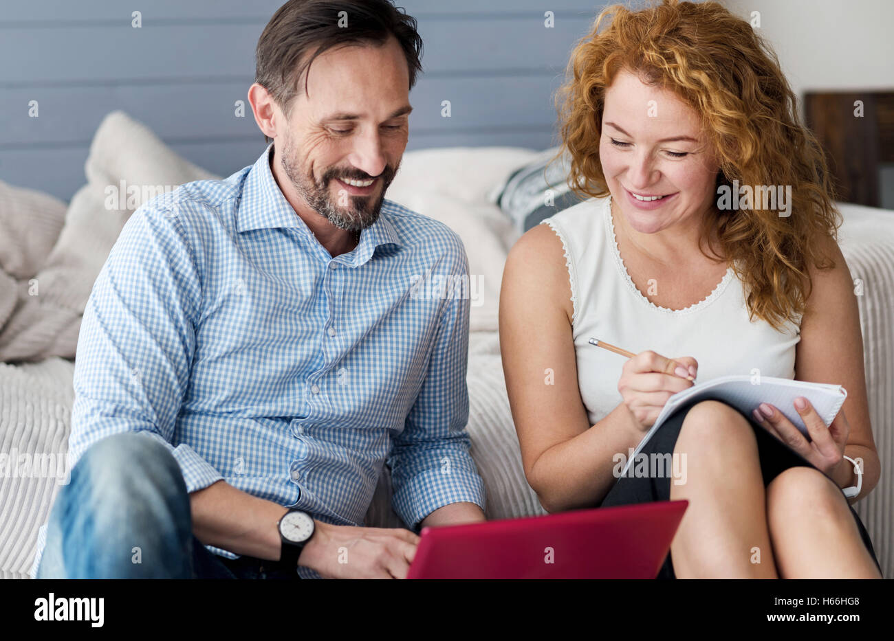Smiling couple using laptop and making notes Stock Photo - Alamy