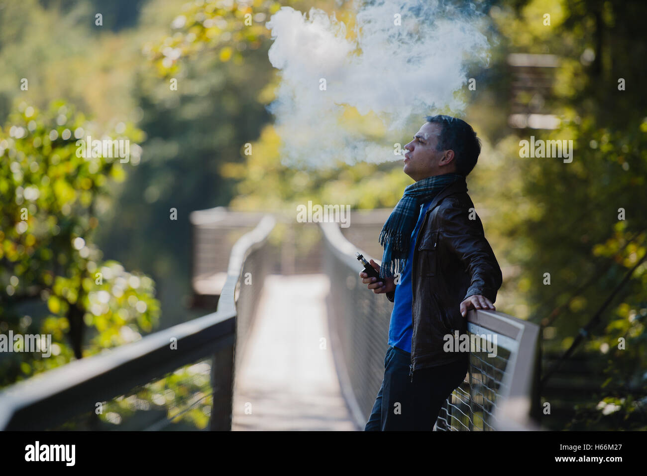 Young man with custom box mode vape device vaping an electronic ...