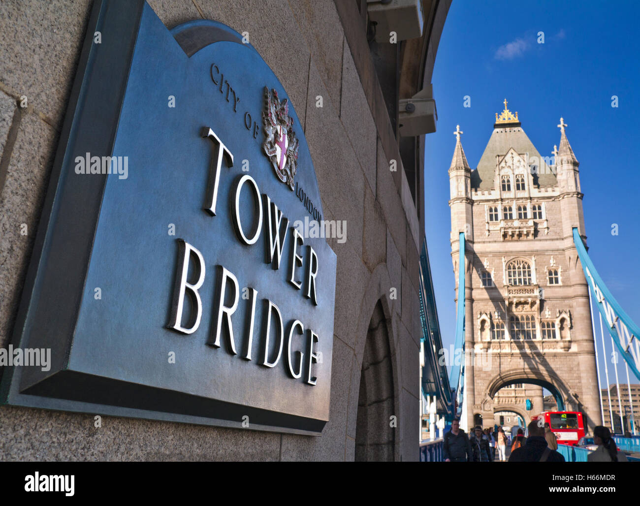Tower Bridge and name plaque with traditional red bus in background ...