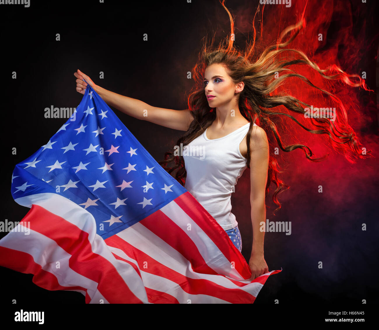 Attractive young girl holding a US flag on the flagpole. She a T-shirt ...
