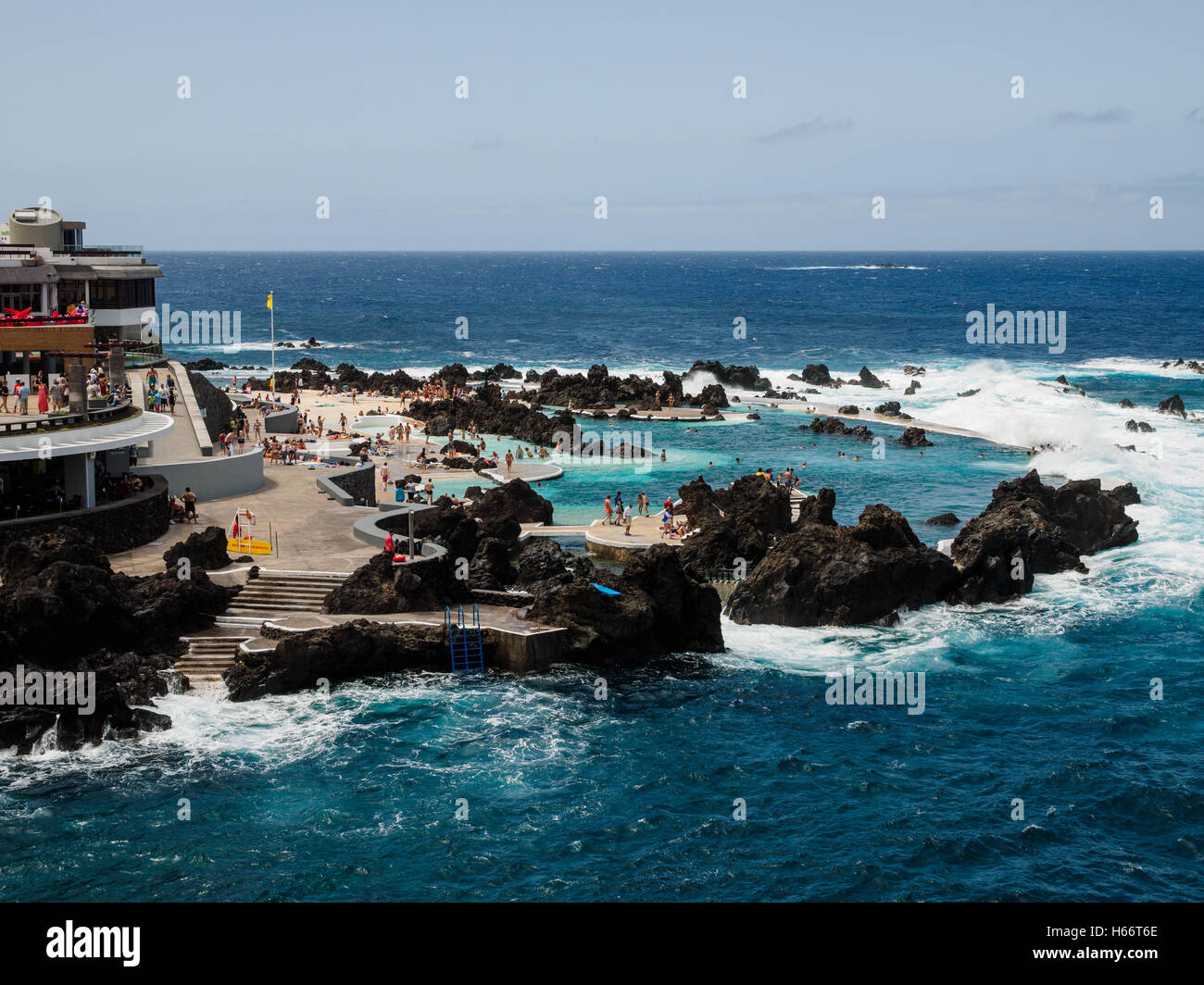 Tourists and local people enjoy a bath in the open air Atlantic Ocean ...