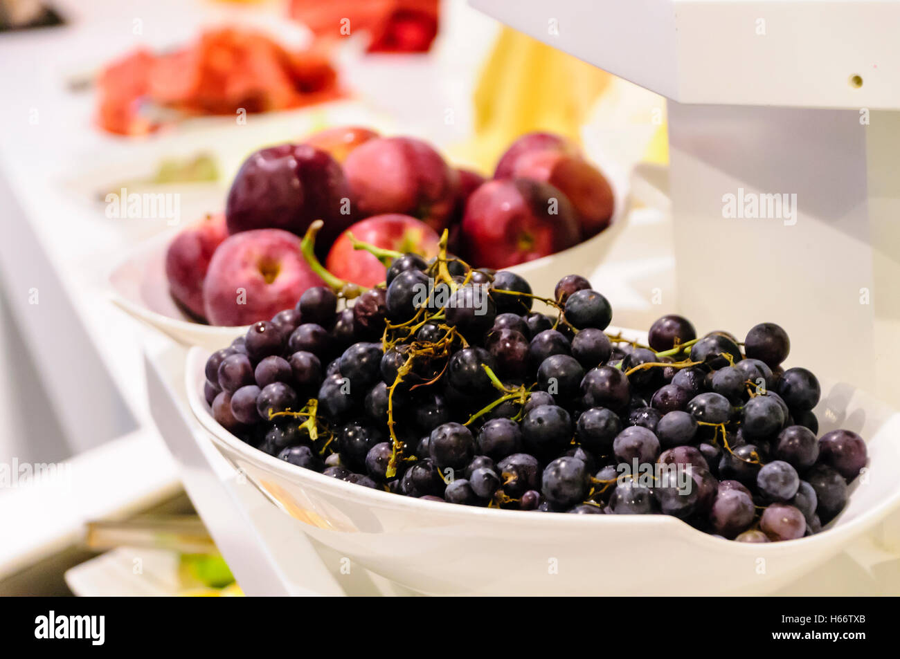 Grapes, apples, and melon in white bowls in a hotel Stock Photo - Alamy