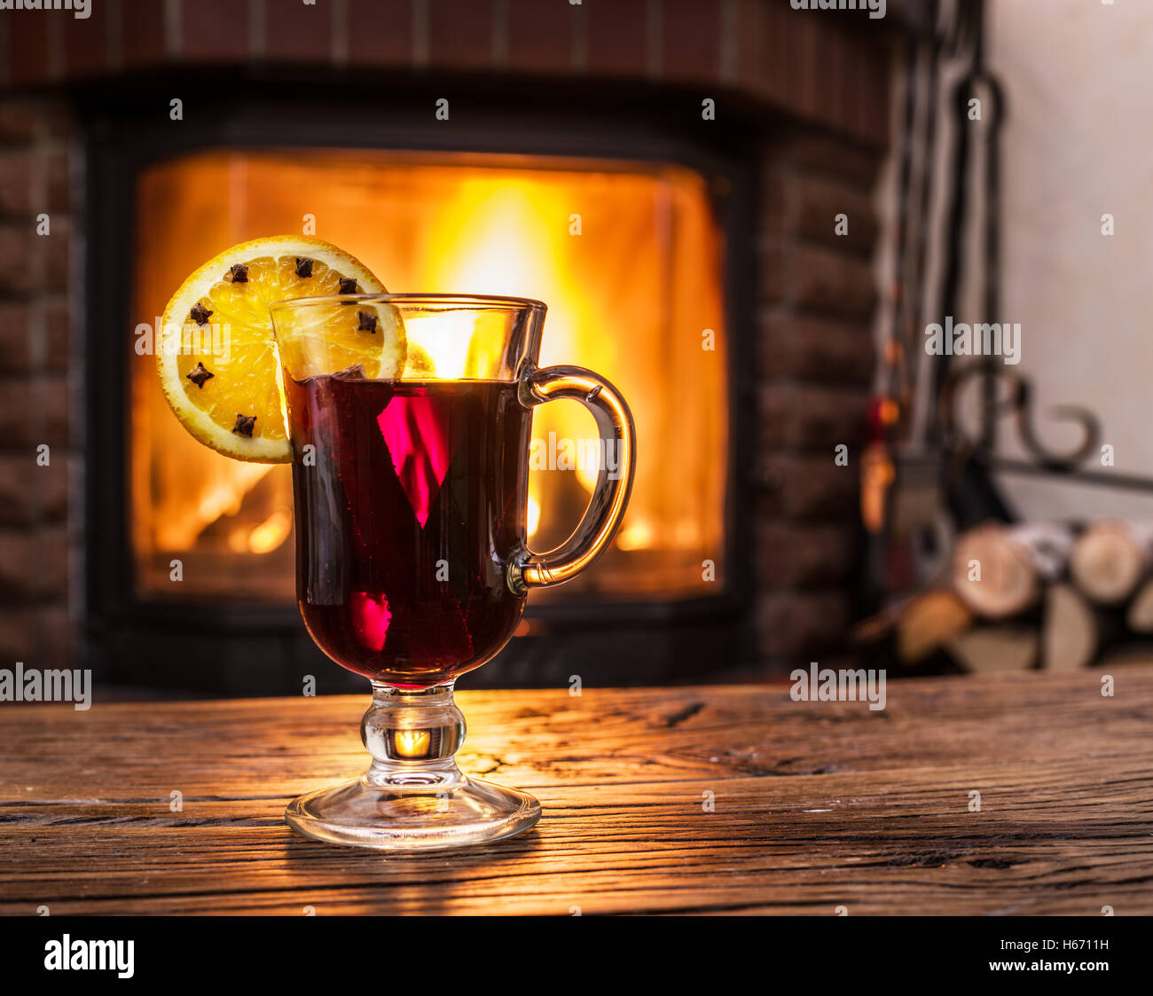 Hot mulled wine with orange slice, cloves and cinnamon stick. Fireplace ...