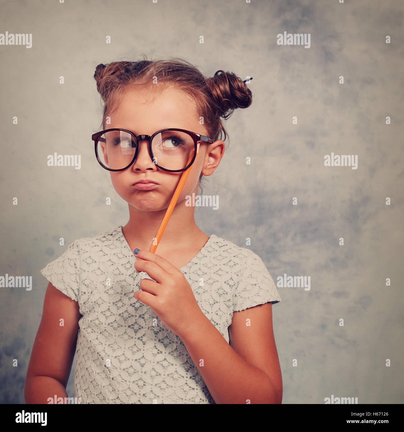 Thinking grimacing kid girl in glasses looking up and have an idea ...
