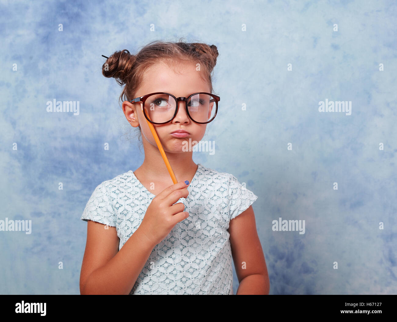 Thinking grimacing kid girl in glasses looking up and have an idea ...
