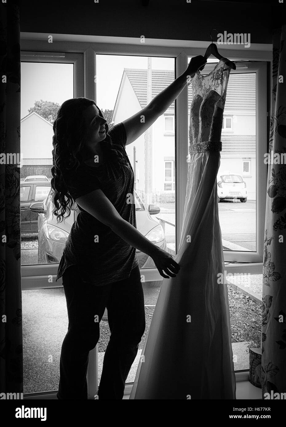 Bride getting ready for her wedding, holding up her dress and looking ...