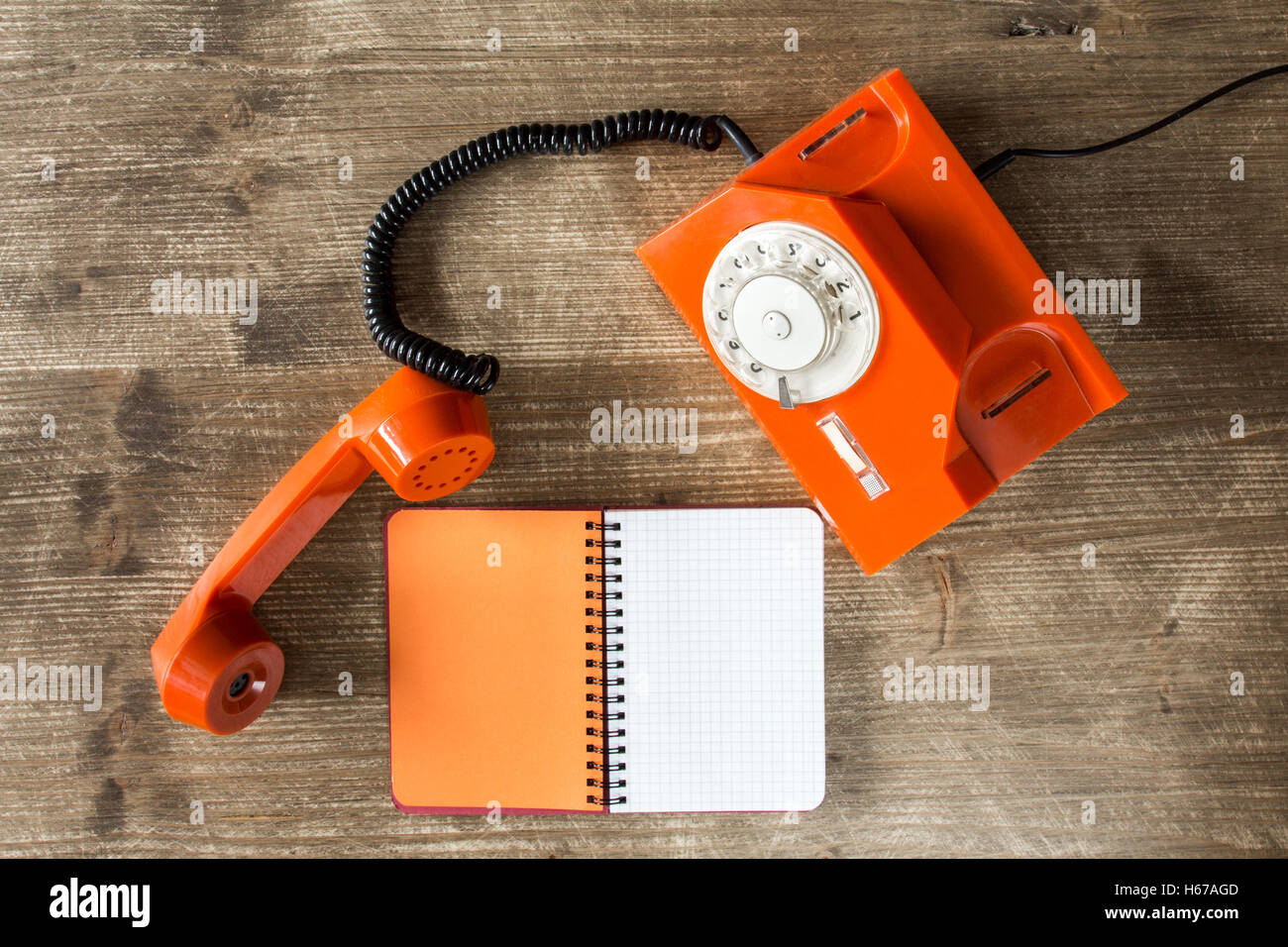Old orange telephone and blank notebook on wooden table. Top view Stock ...