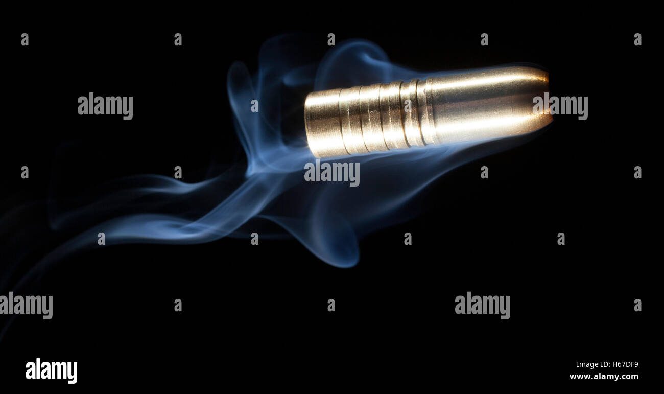 Bronze colored bullet with smoke behind on a black background Stock ...