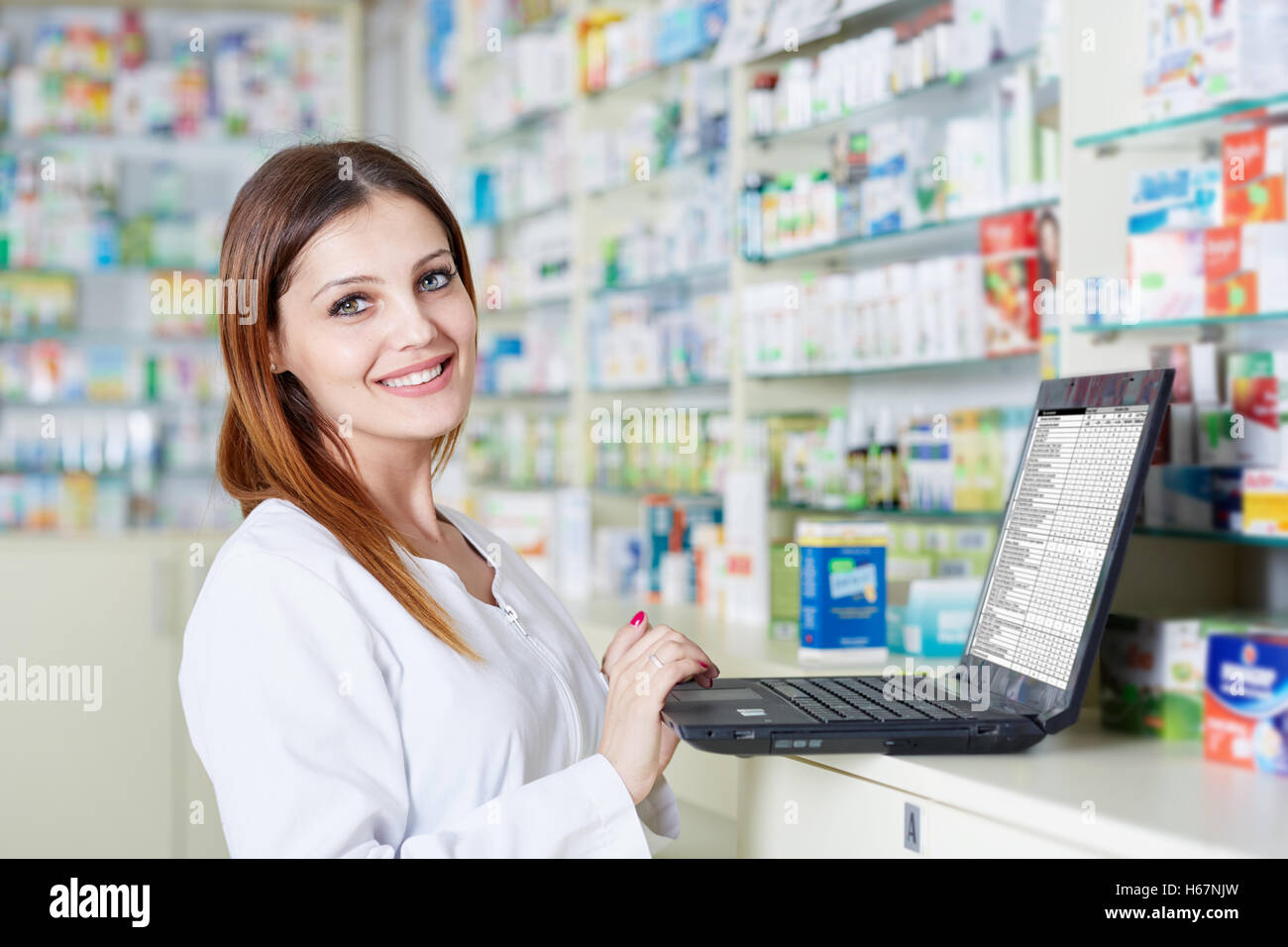 Female pharmacist checking medicine stock availability on her laptop ...