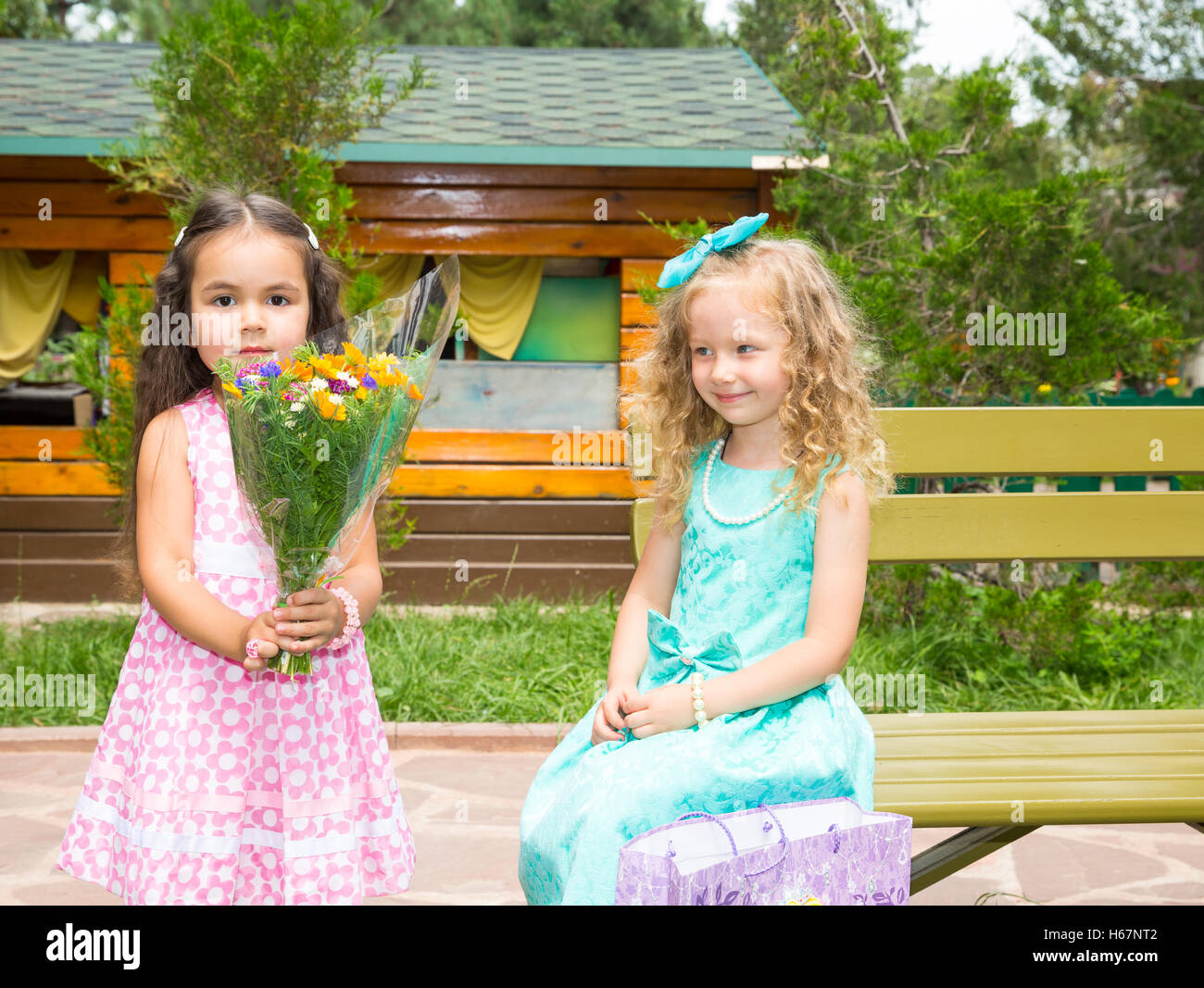 Two girlfriends. Adorable little children with bouquet of flowers on ...