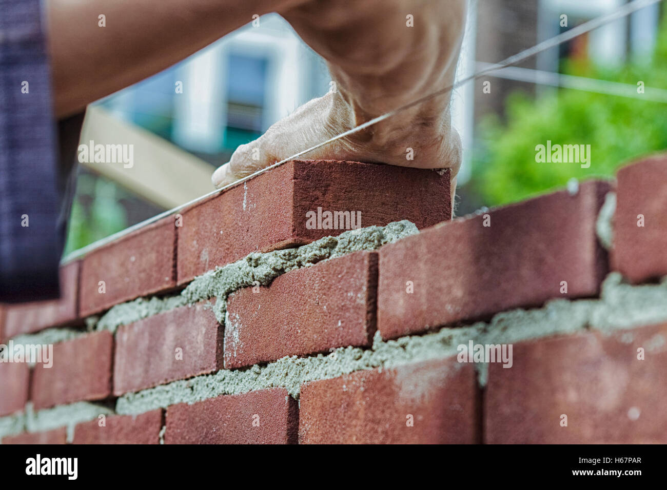 Hand pushes down brick in cement Stock Photo - Alamy