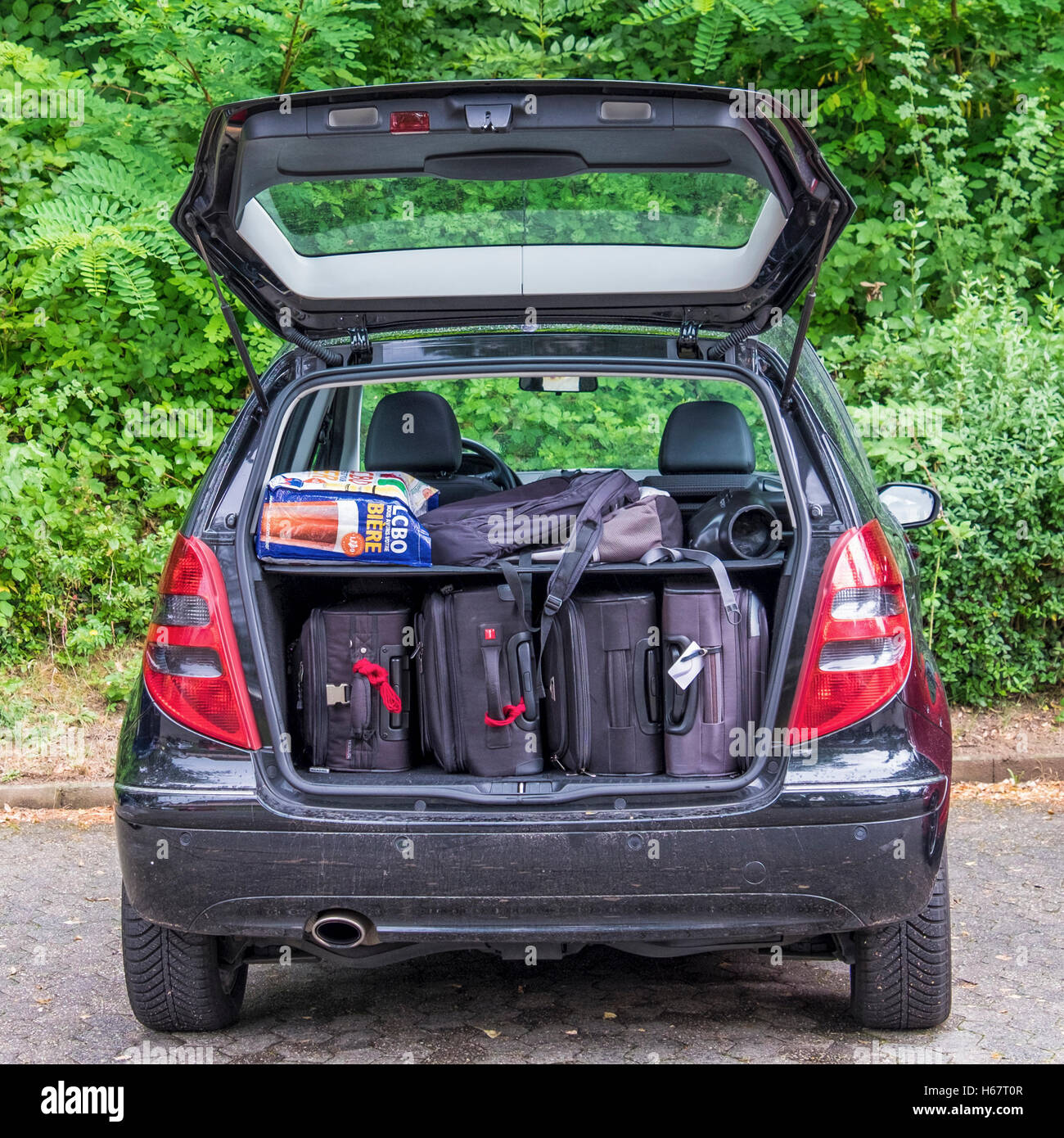 Black car with open boot packed with four suitcases for holiday trip ...