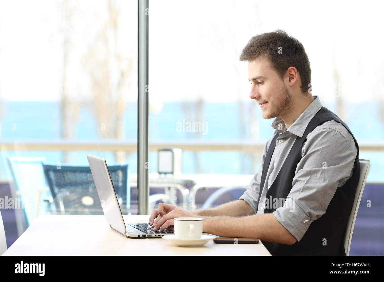 Profile of a businessman working on line typing in a laptop sitting in ...