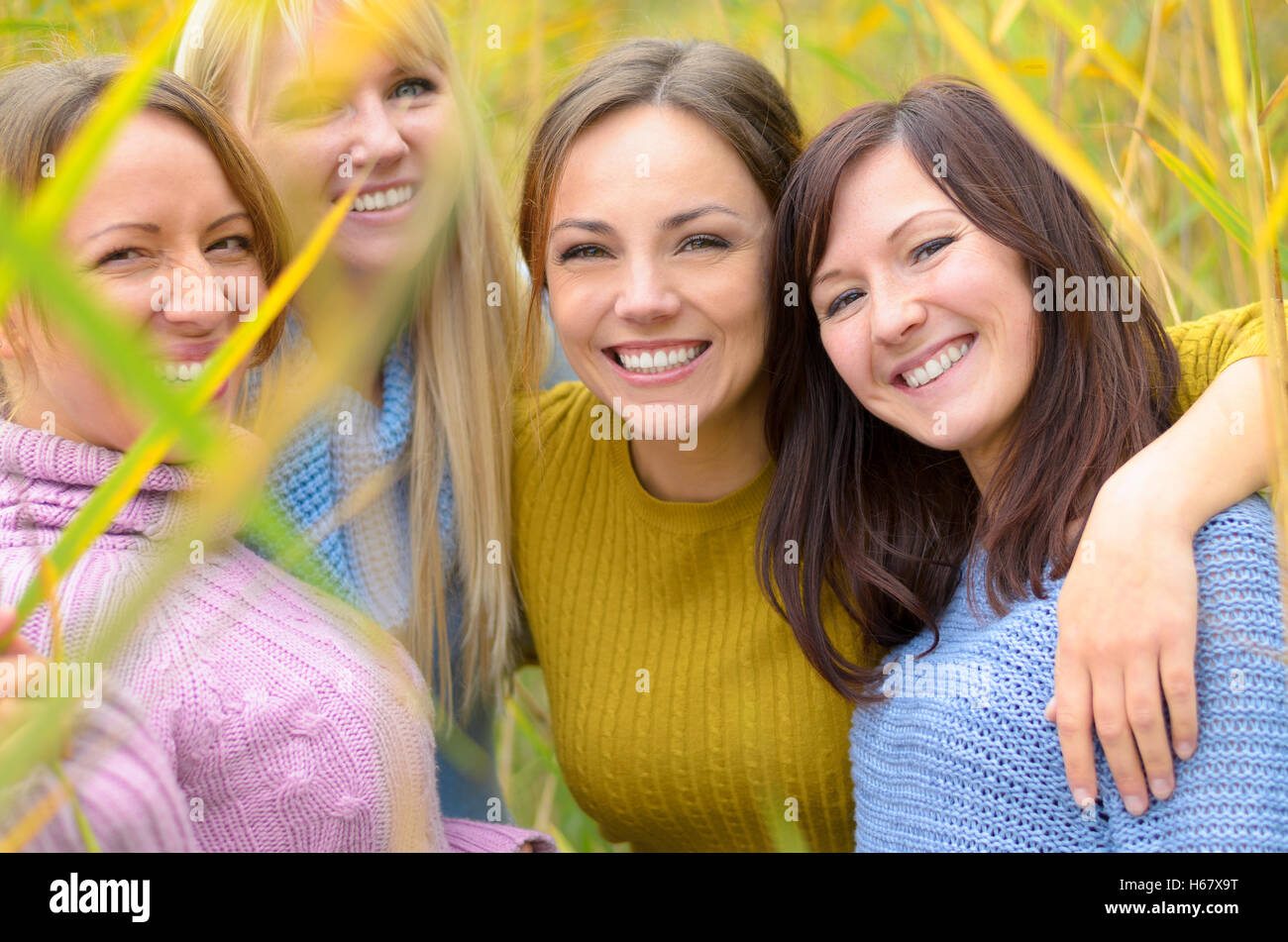 Cute pretty young woman grinning at the camera as she stands arm in arm ...