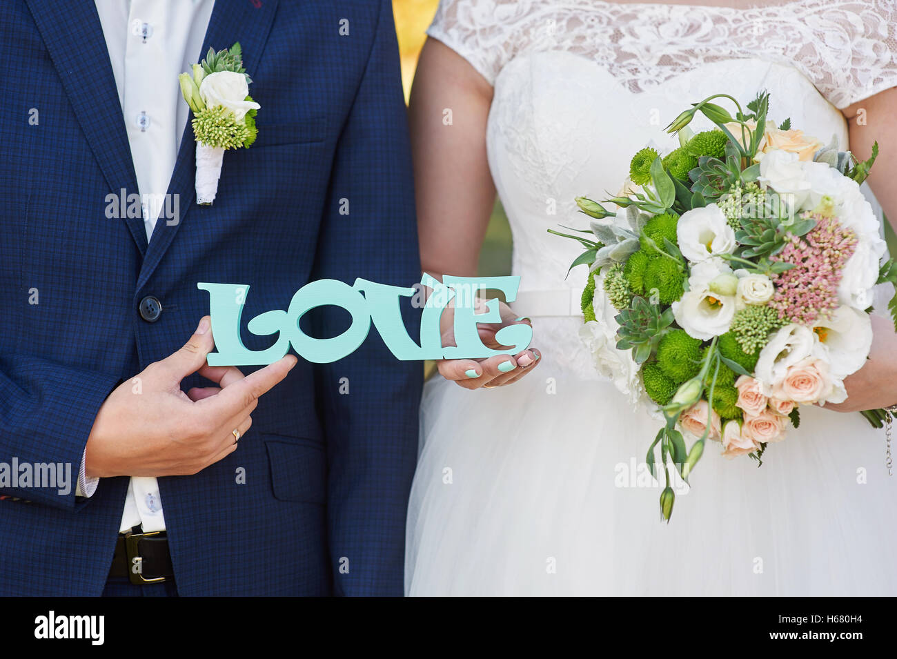 bride and groom holding wooden word love Stock Photo - Alamy