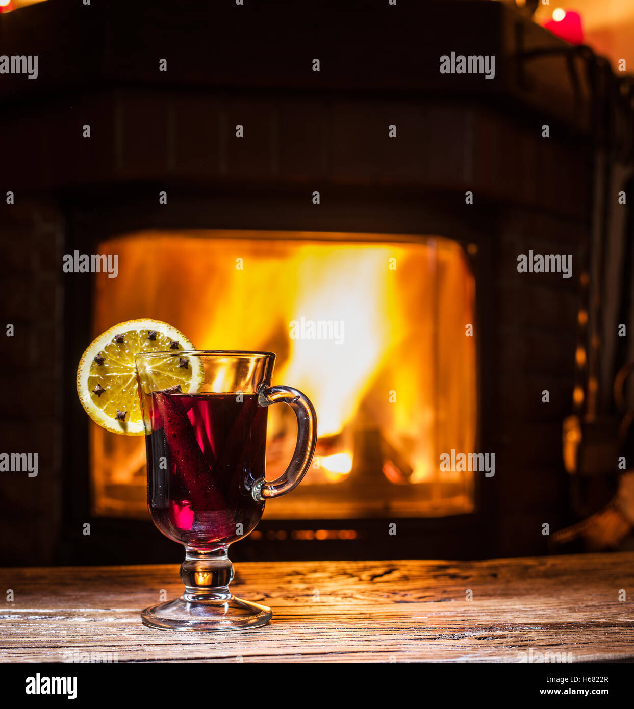 Hot mulled wine with orange slice, cloves and cinnamon stick. Fireplace ...