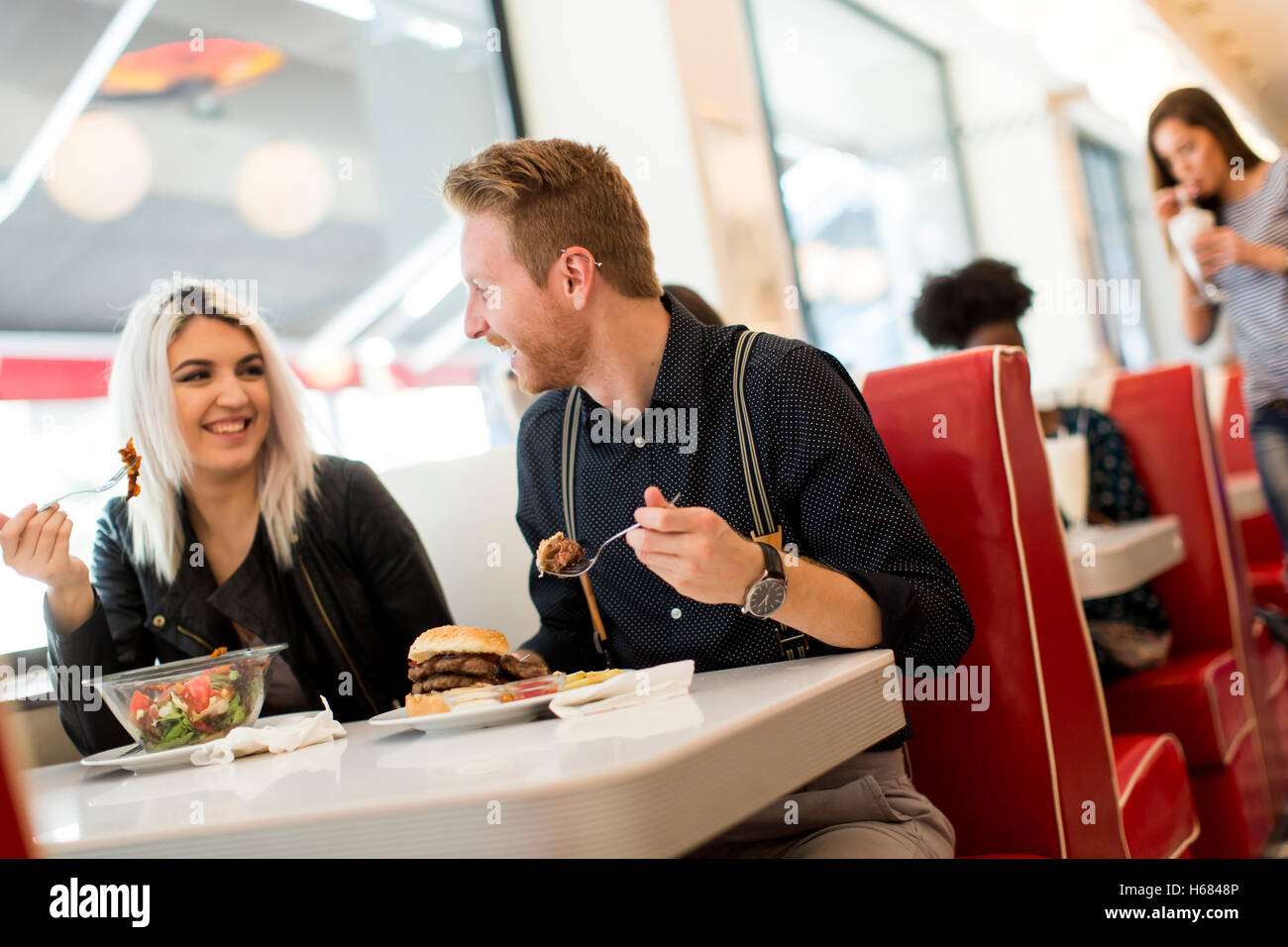 Friends eating fast food at the table in the diner Stock Photo - Alamy