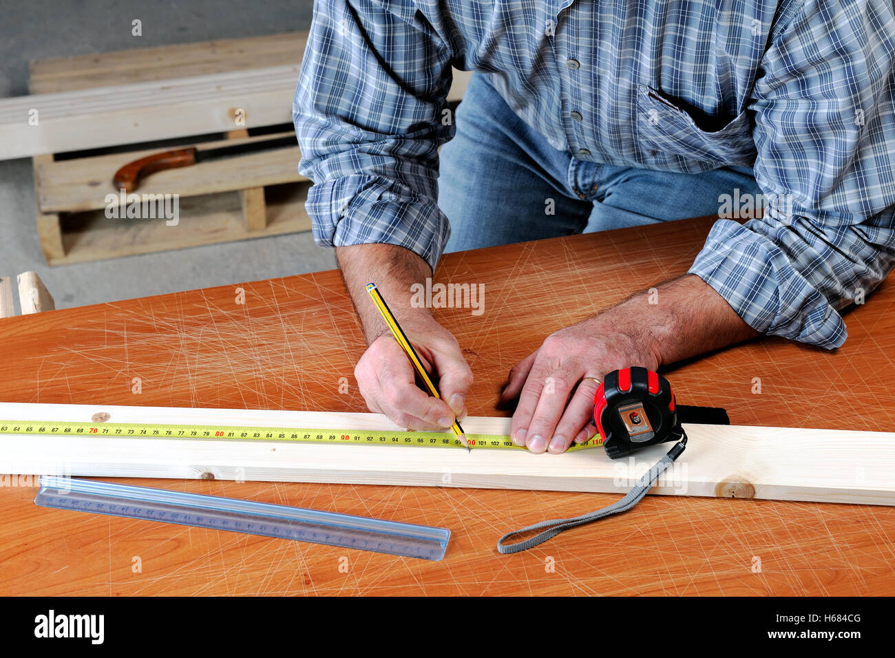 Artisan adult takes the measurement of a strip of wood to manufacture a ...