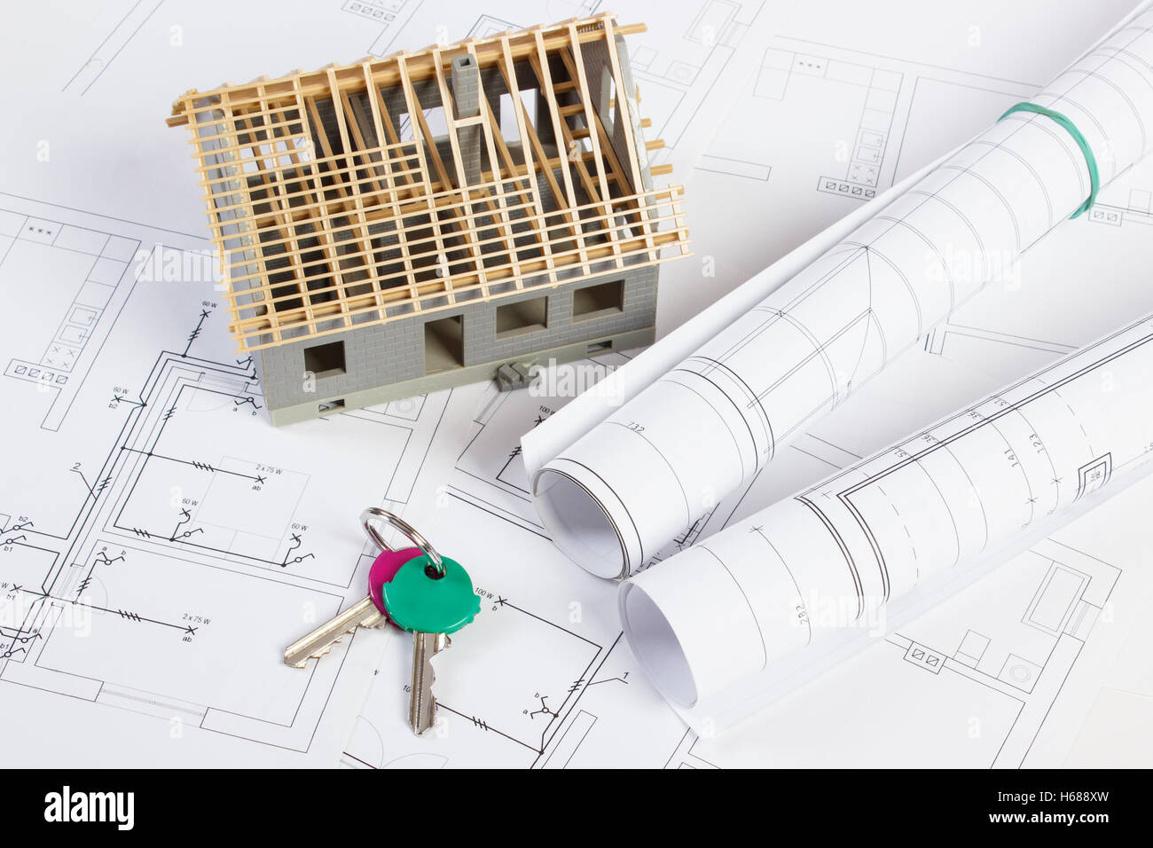 Home keys, small house under construction and rolls of diagrams on ...