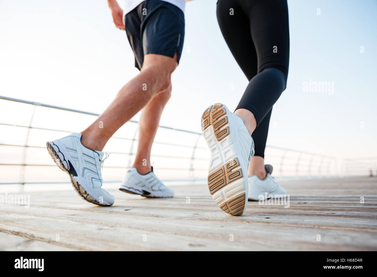 Cropped image of three runners sprinting outdoors at the beach pier ...