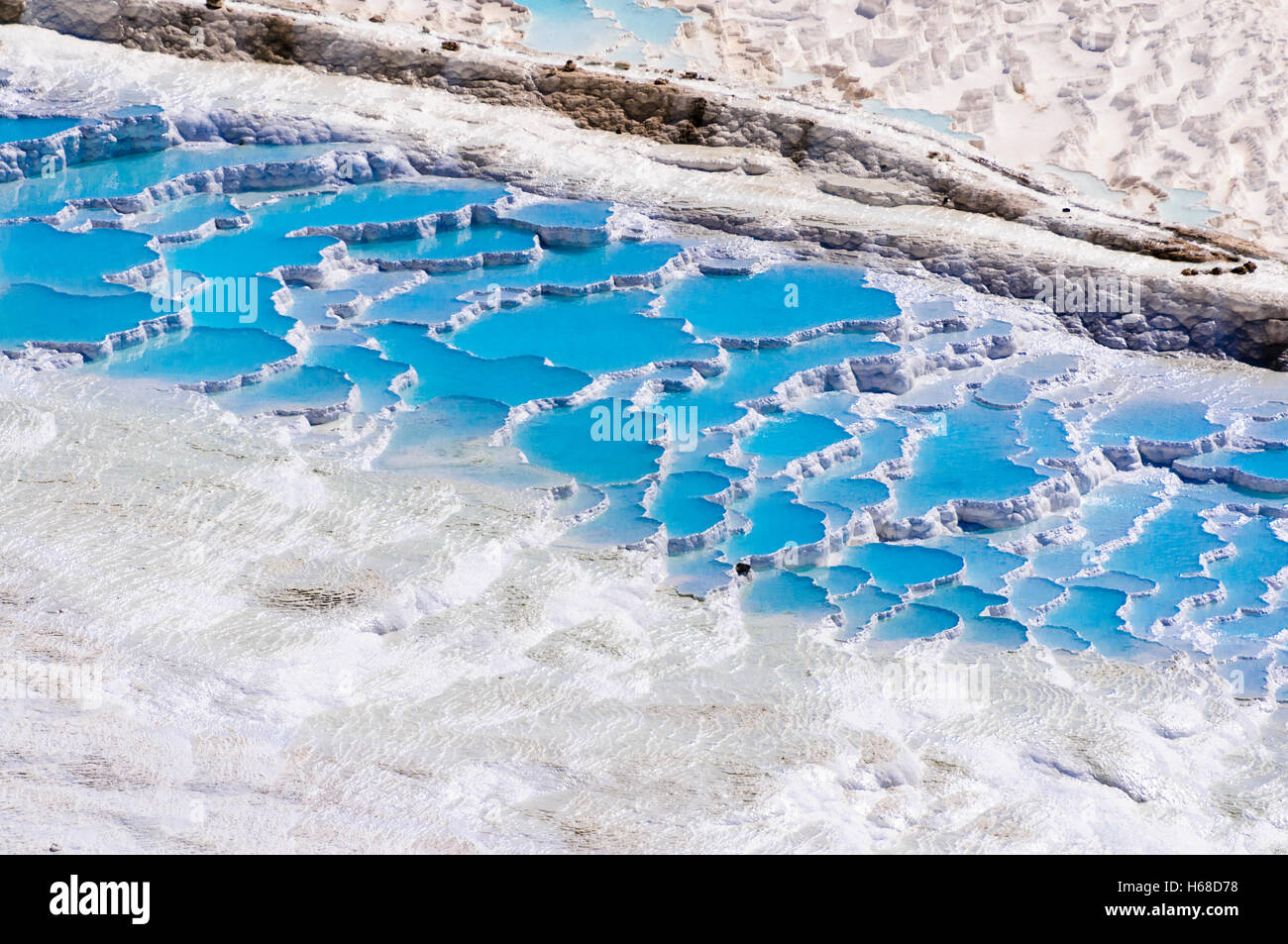 Terraced travertines at the thermal springs pools with bright blue ...
