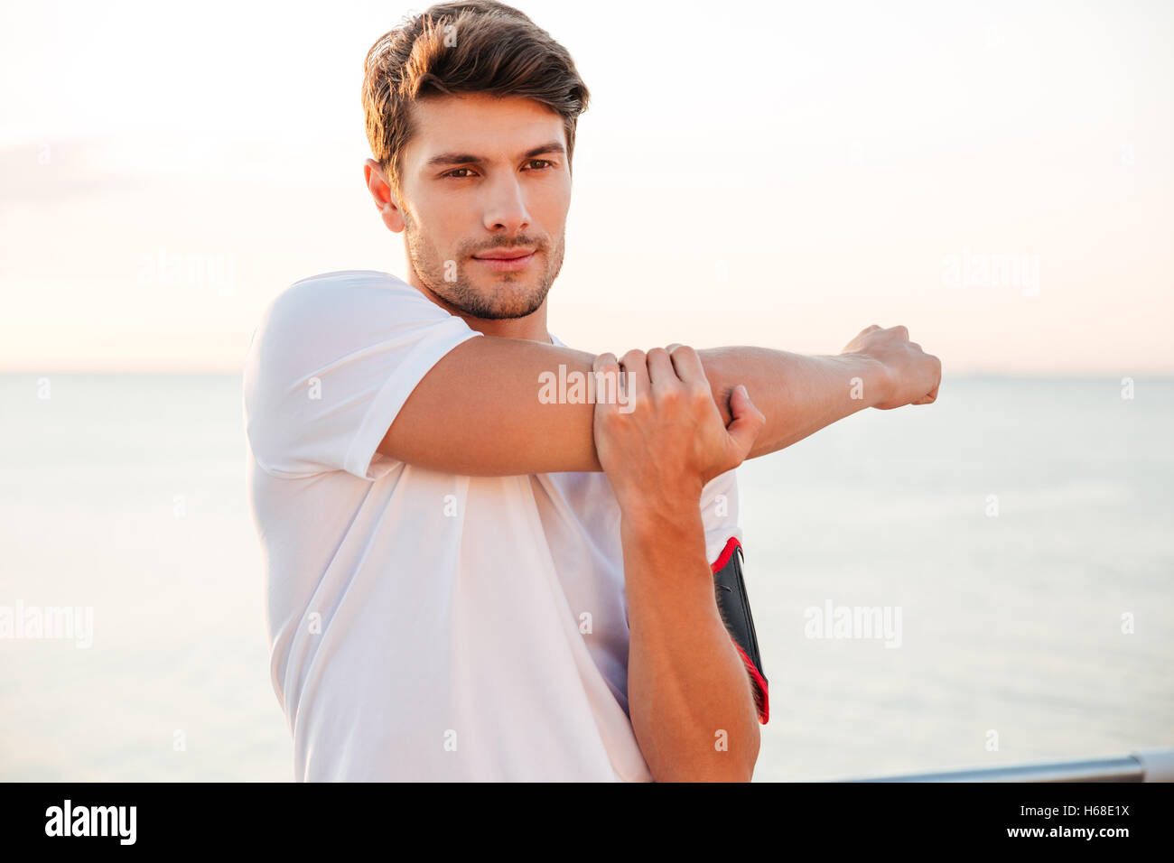 Handsome young muscular man stretching his arms while standing at the ...